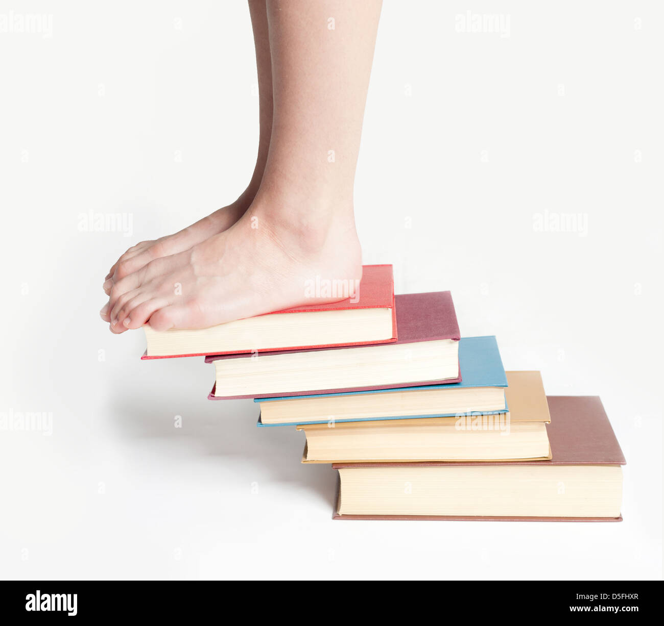 Person standing on a stack of books Stock Photo - Alamy