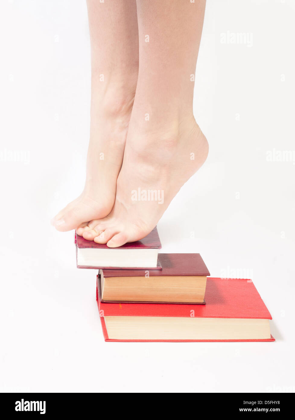 Person standing on a stack of books Stock Photo - Alamy