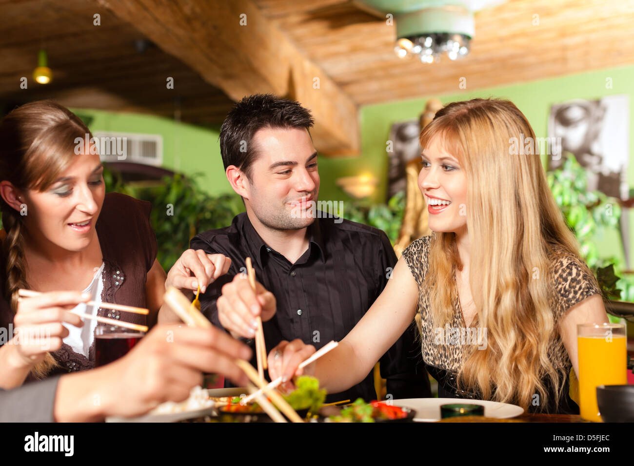 Young people eating in a Thai restaurant, they eating with chopsticks ...