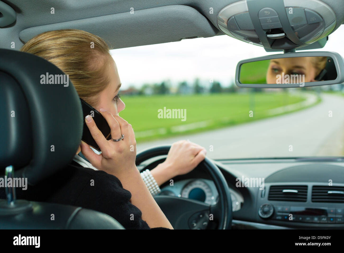 Young woman with telephone having phone conversation while driving car ...