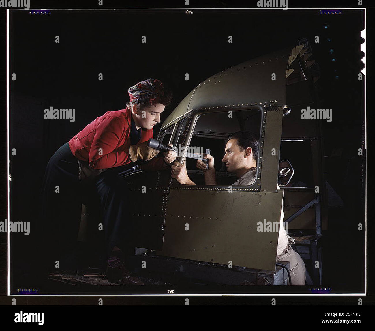This image shows a riveting team working on the cockpit shell of a B-25 ...