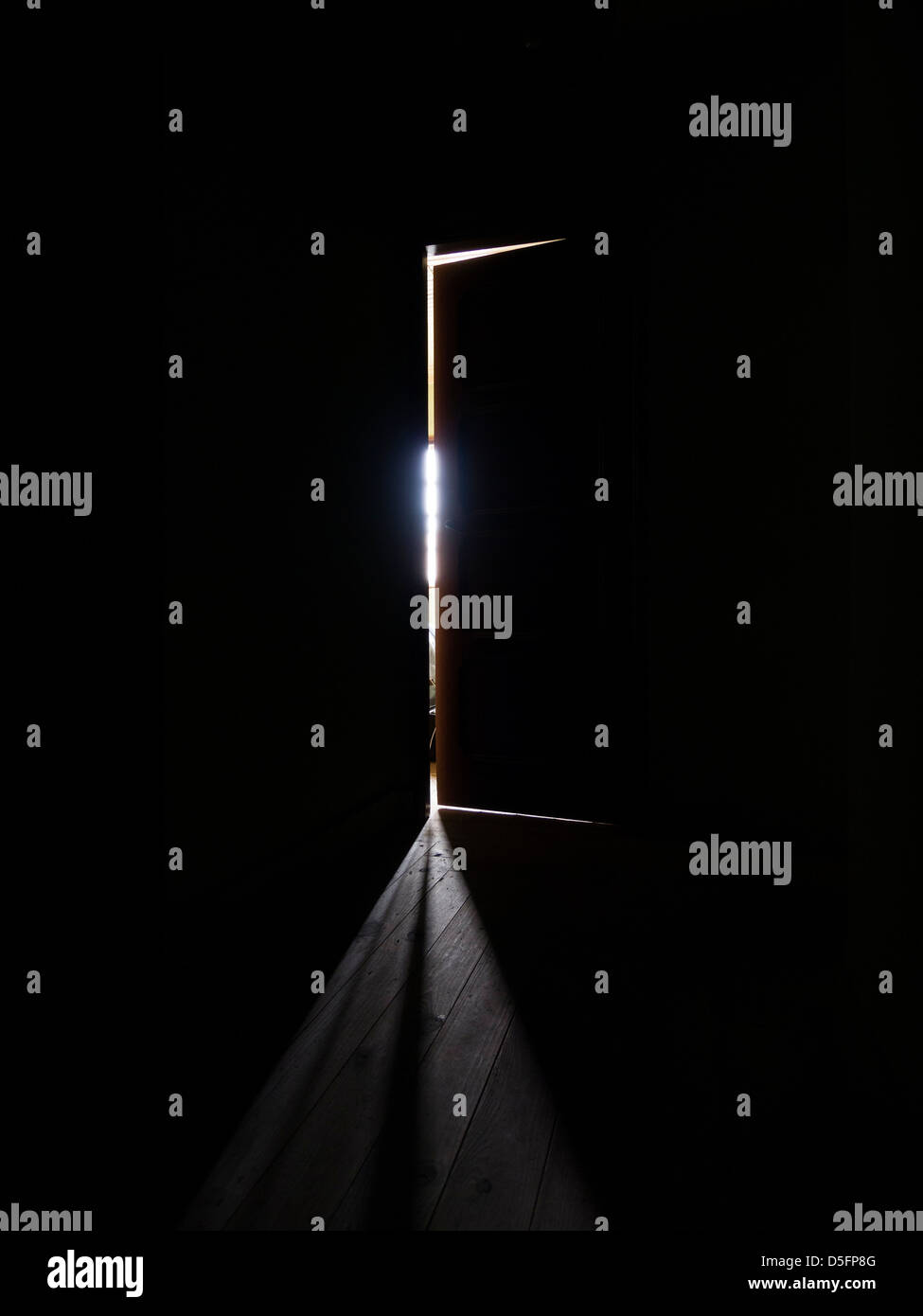 Door ajar at the end of a dark corridor letting some light trough in a ...