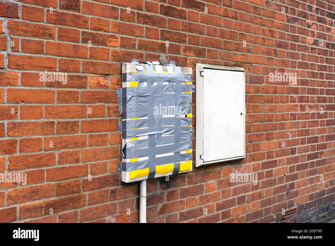 Broken service meter box on brick wall of a house held together with ...