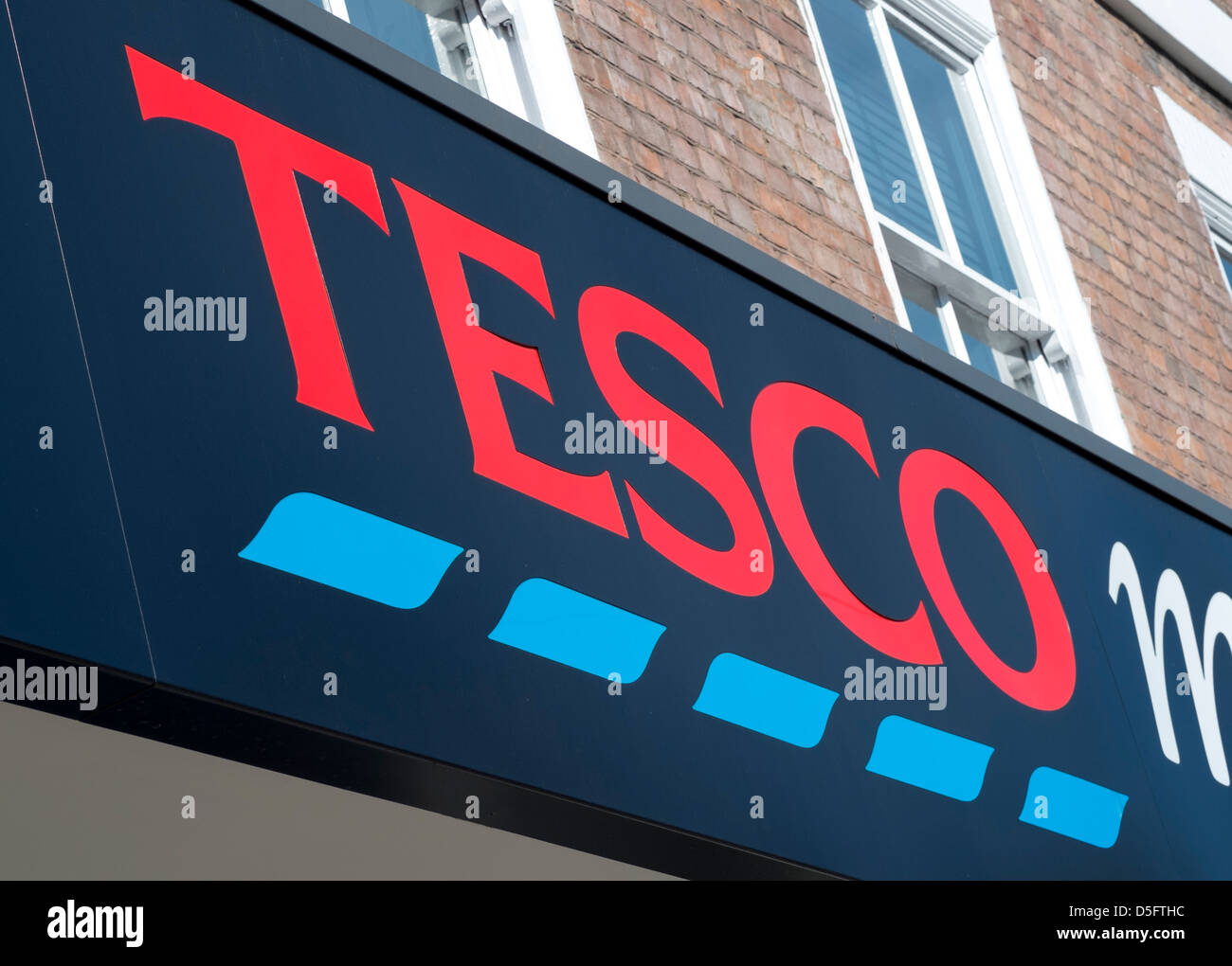 Looking up at Tesco supermarket name and logo above the entrance to one ...