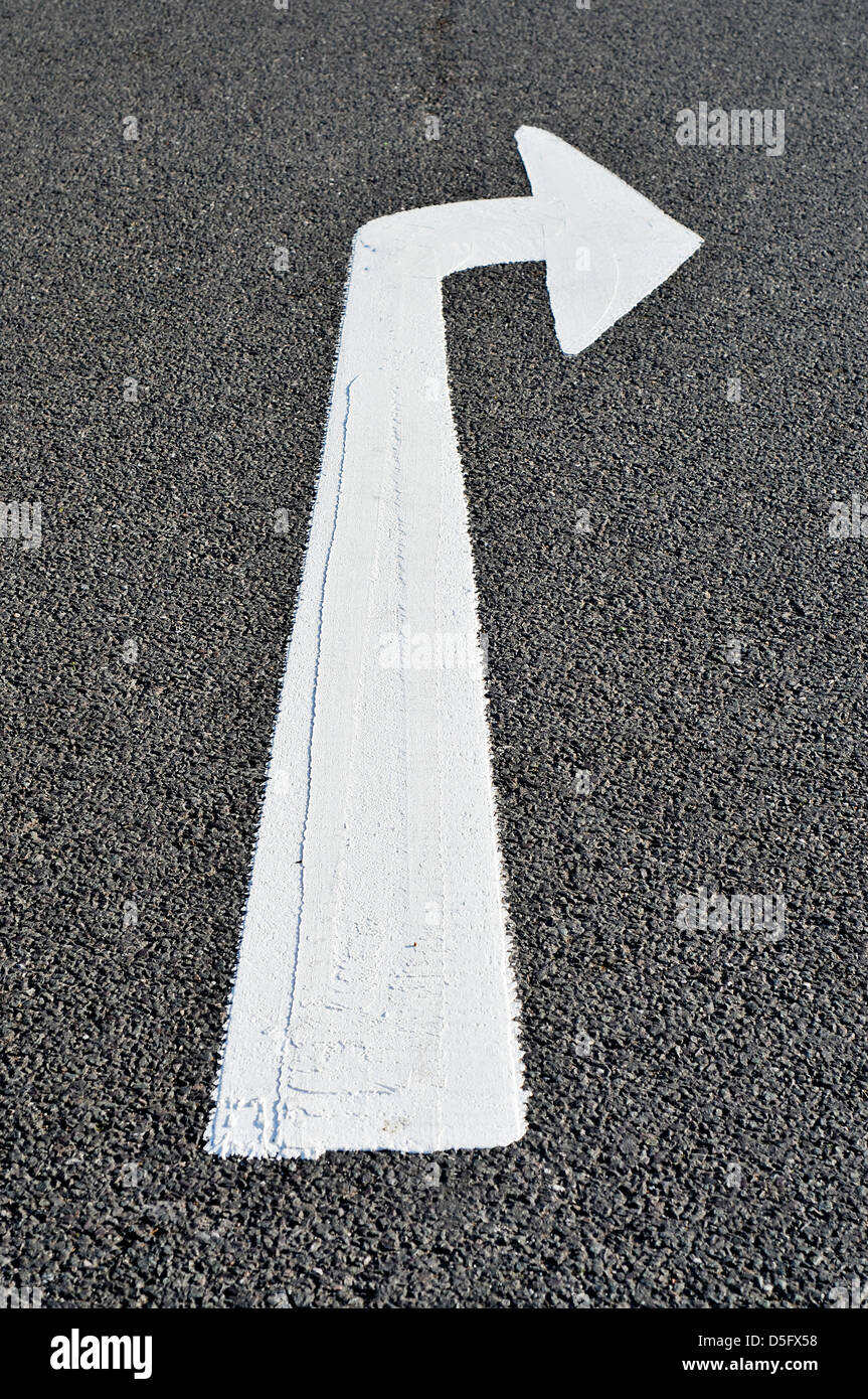 White arrow on road surface pointing out direction Stock Photo - Alamy