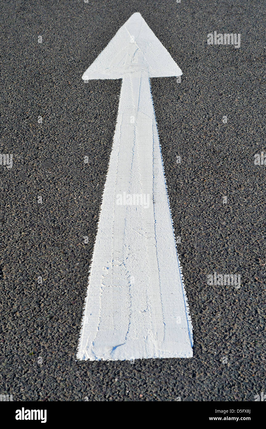 White arrow on road surface pointing out direction Stock Photo - Alamy