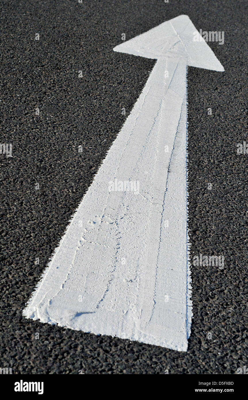 White arrow on road surface pointing out direction Stock Photo - Alamy