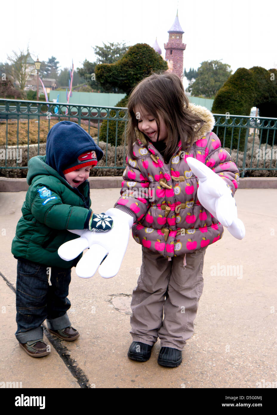 A toddler slaps the hand of his big sister who is wearing over sized ...