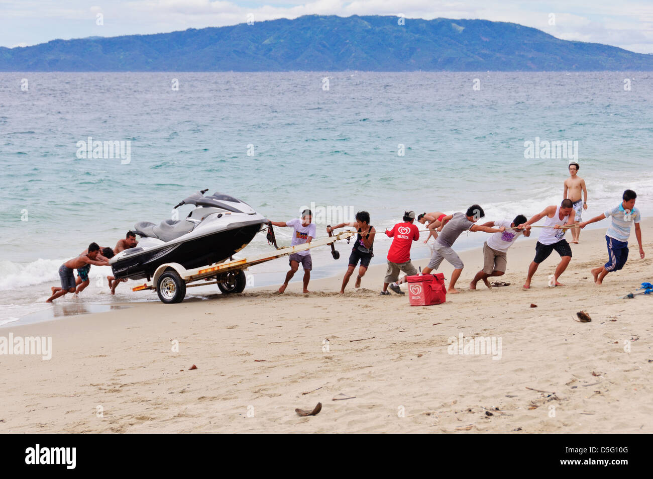 Group of people pulling a jet-ski out of the ocean on a boat trailer ...