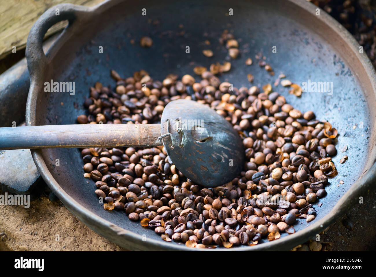 Traditional coffee beans roasting in metal basin with spoon, shallow ...