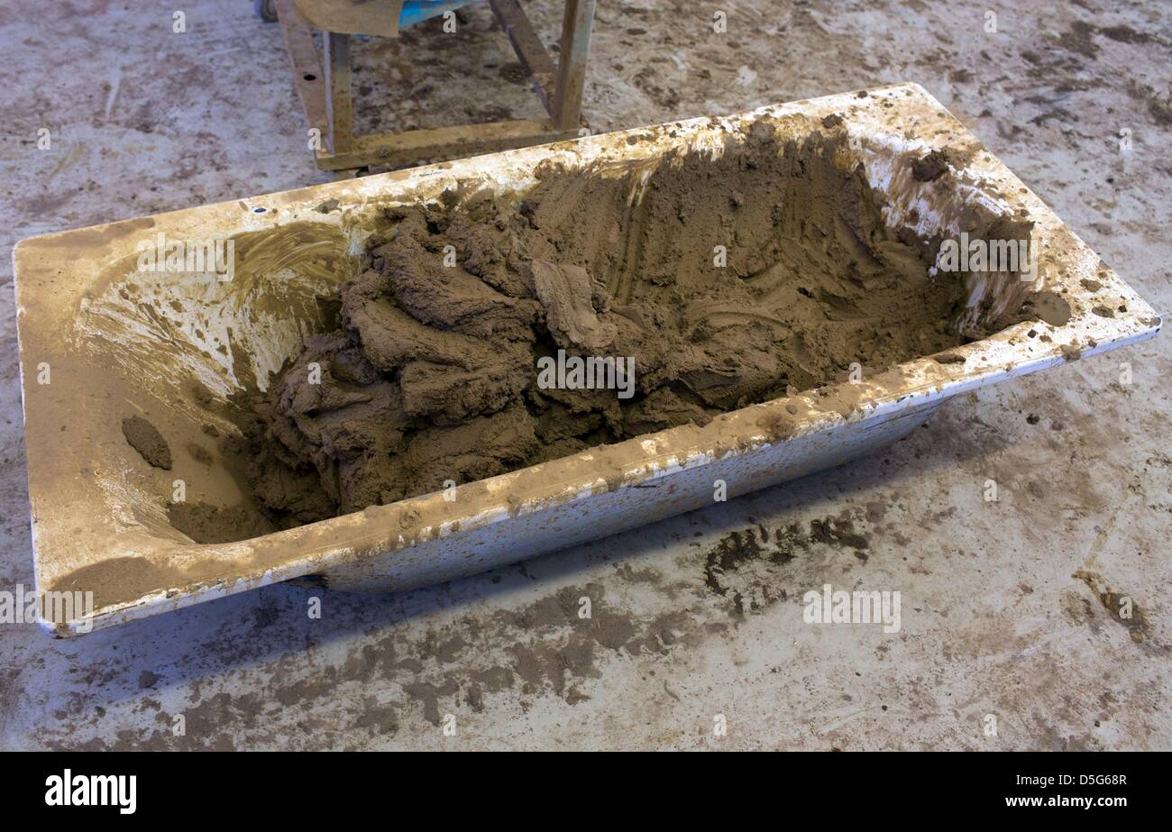 A clay mixture for the manufacture of lay bricks lies on an old bathtub ...