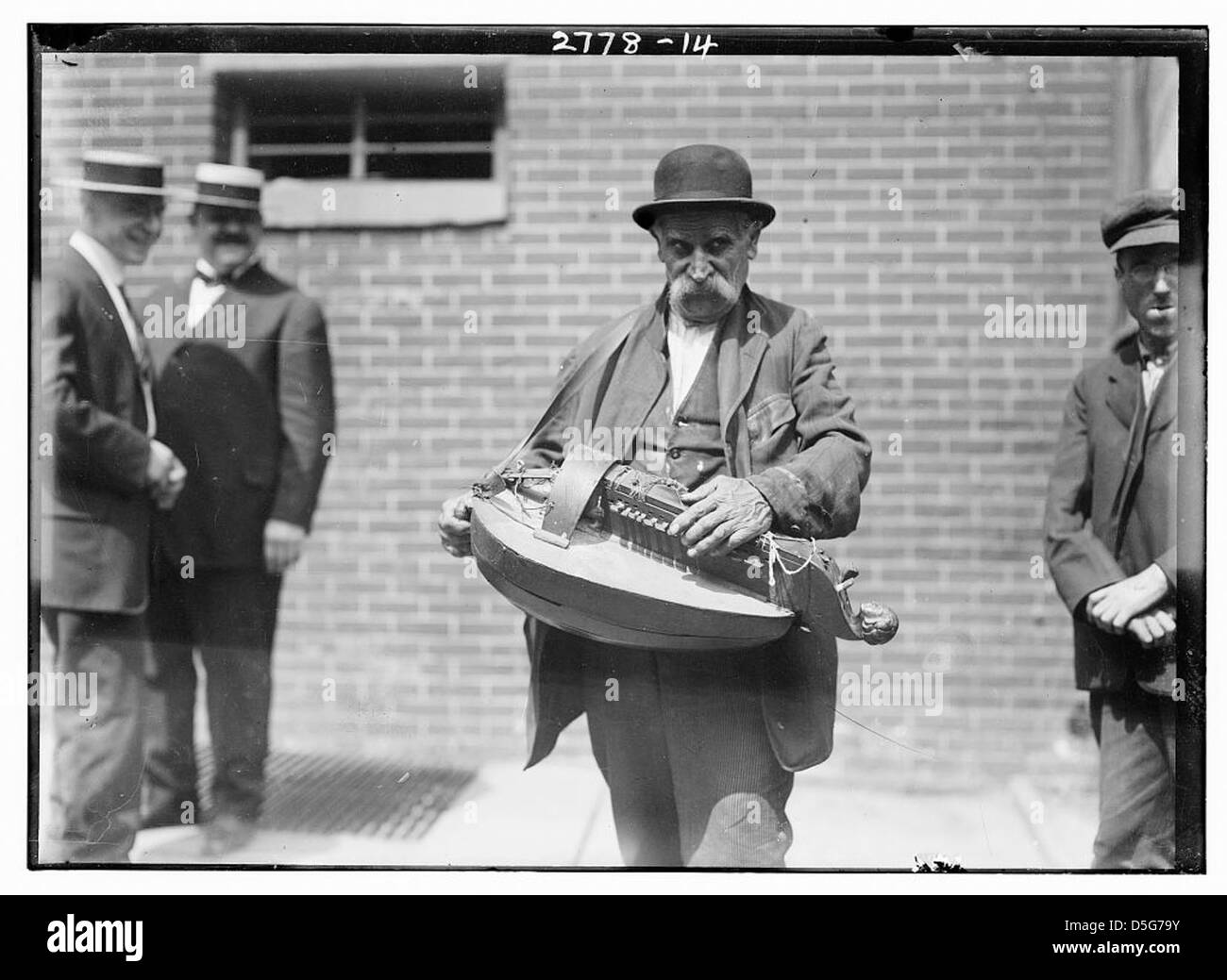 A photograph of a man playing a hurdy-gurdy, an early musical ...