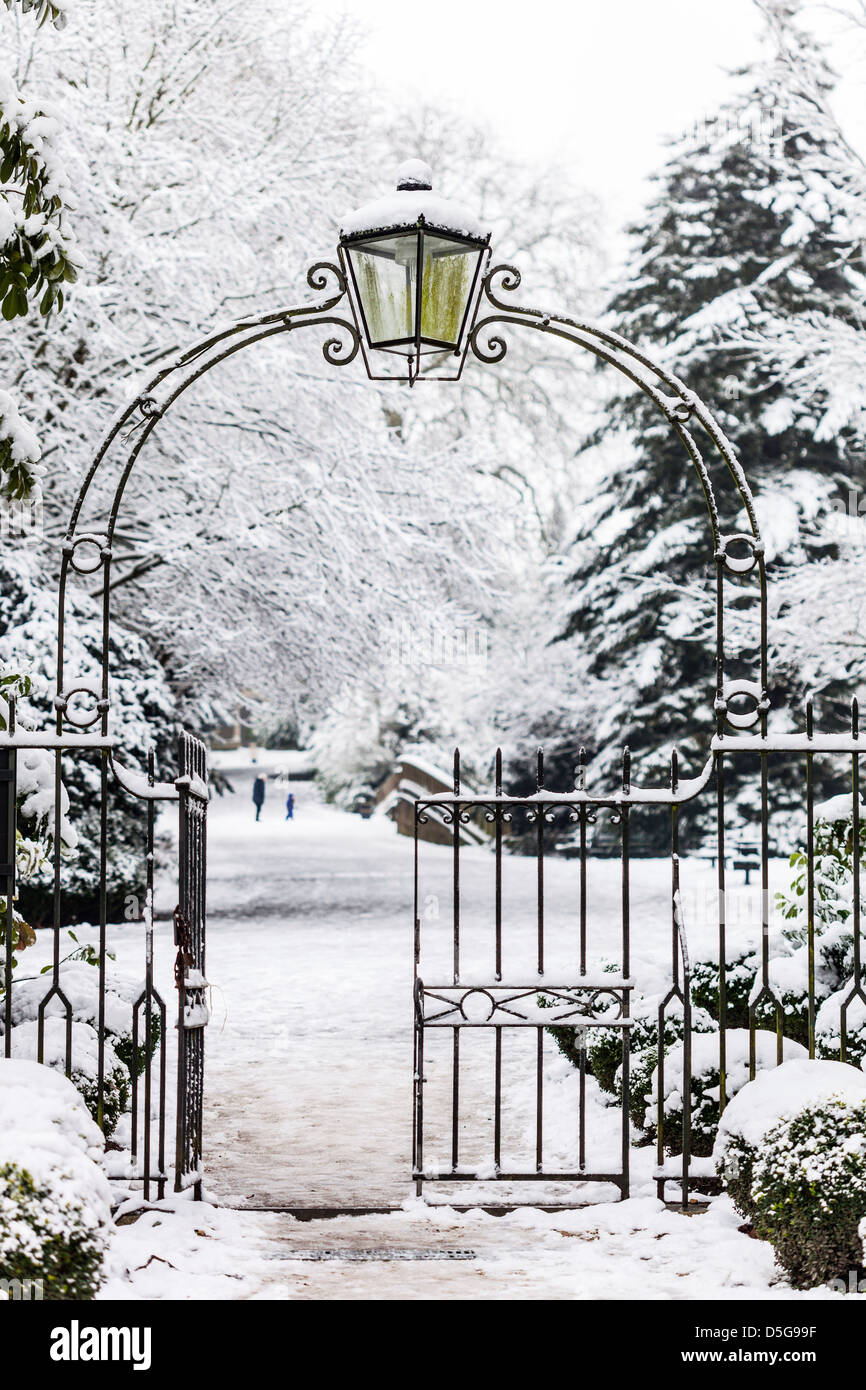 Ornate metal park entrance covered in snow with people out of focus in ...