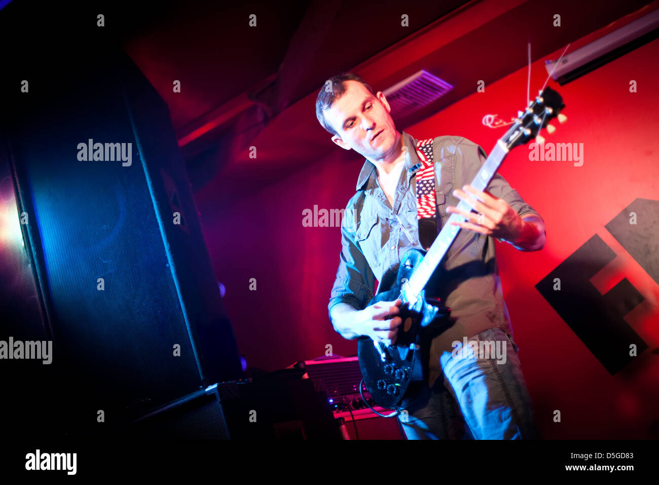 musician plays a guitar on a red background Stock Photo - Alamy