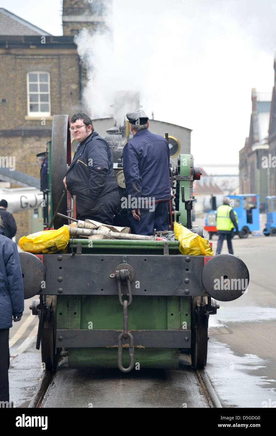 Men in overalls drive a small steam shunting engine in Chatham Dockyard ...