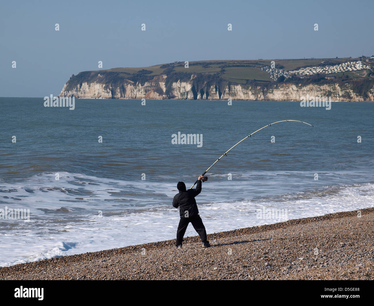 A fisherman beach casting from Seaton beach Stock Photo - Alamy