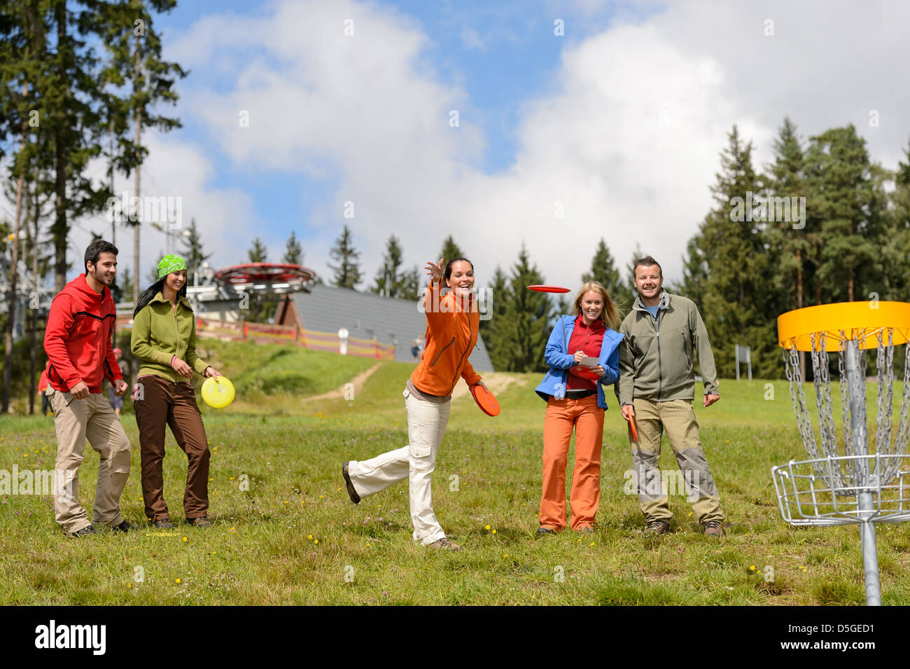 Group of friends throwing frisbee disc to basket in park Stock Photo ...