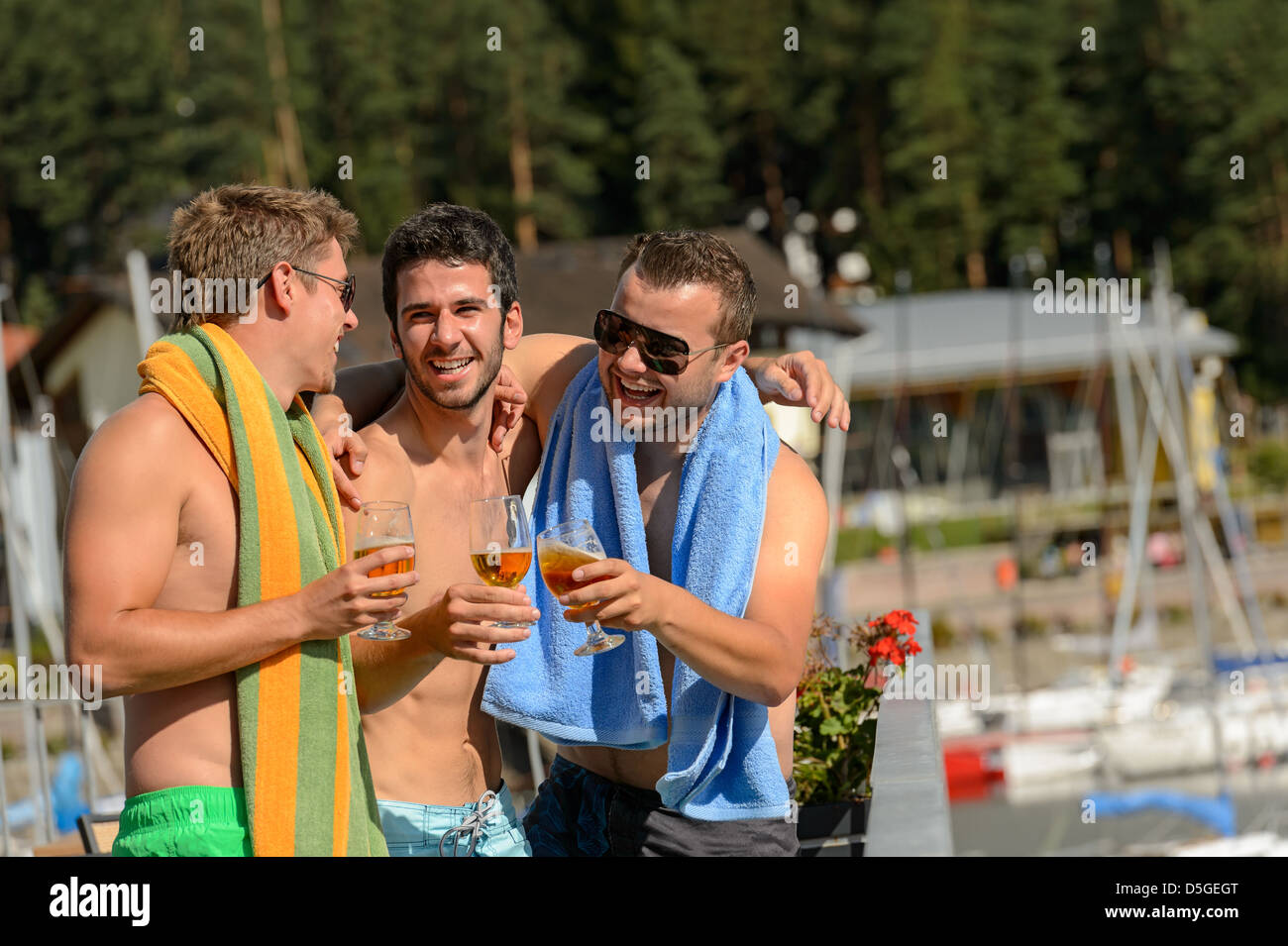Young guys toasting with beer enjoying summer in swimsuits Stock Photo ...