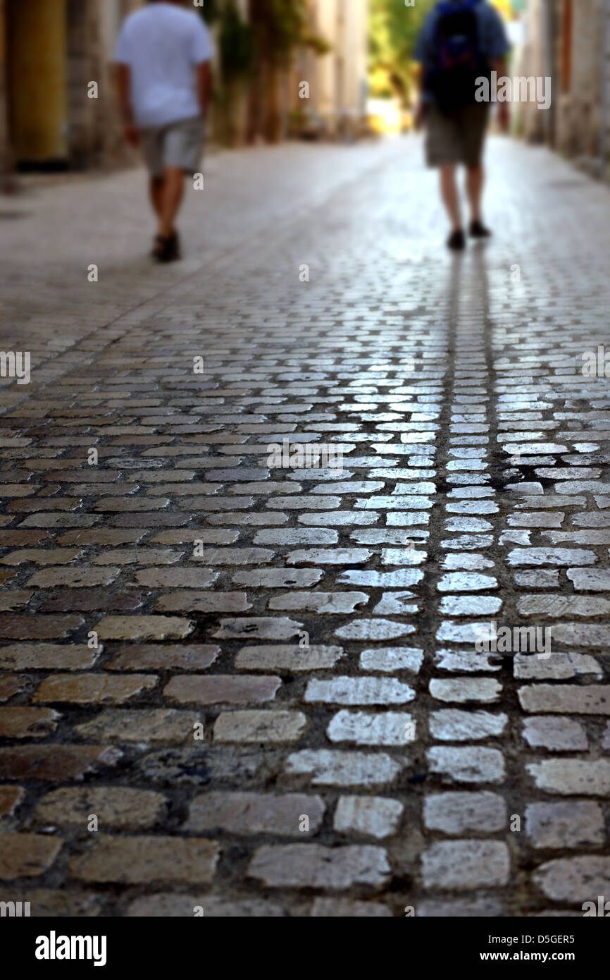 Two people walking down a cobbled street in France Stock Photo - Alamy