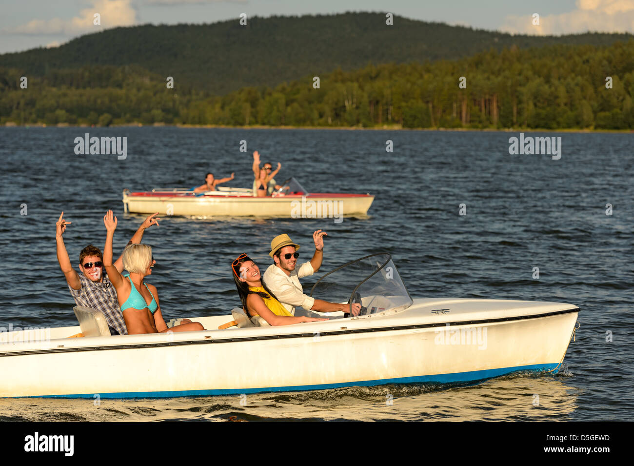 Group of cheerful friends racing with motorboats on river Stock Photo ...