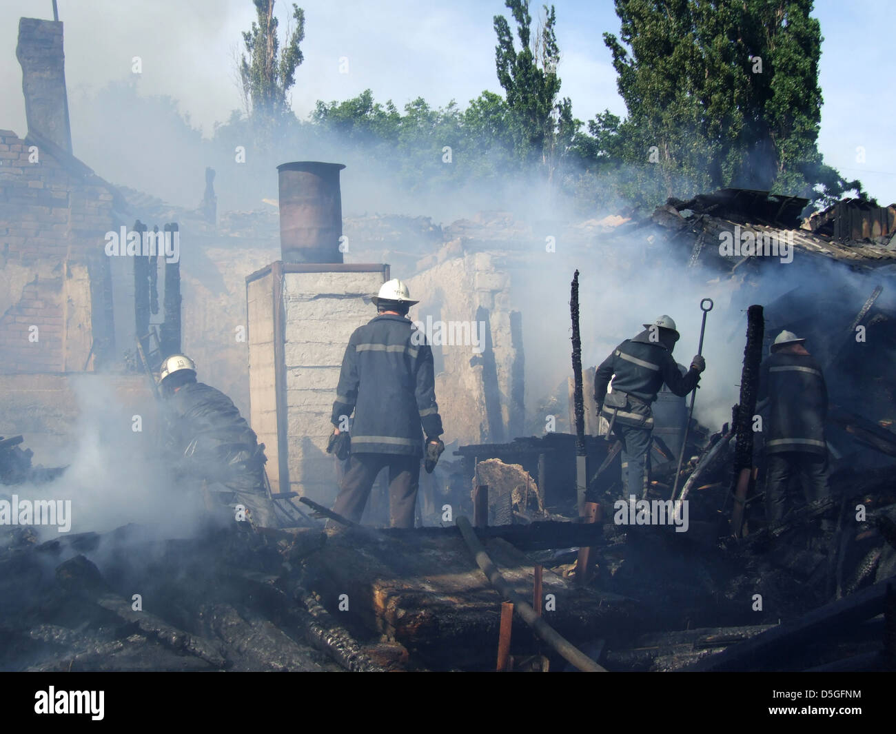 Smoldering remains of a ghetto house with a fireman spraying water ...