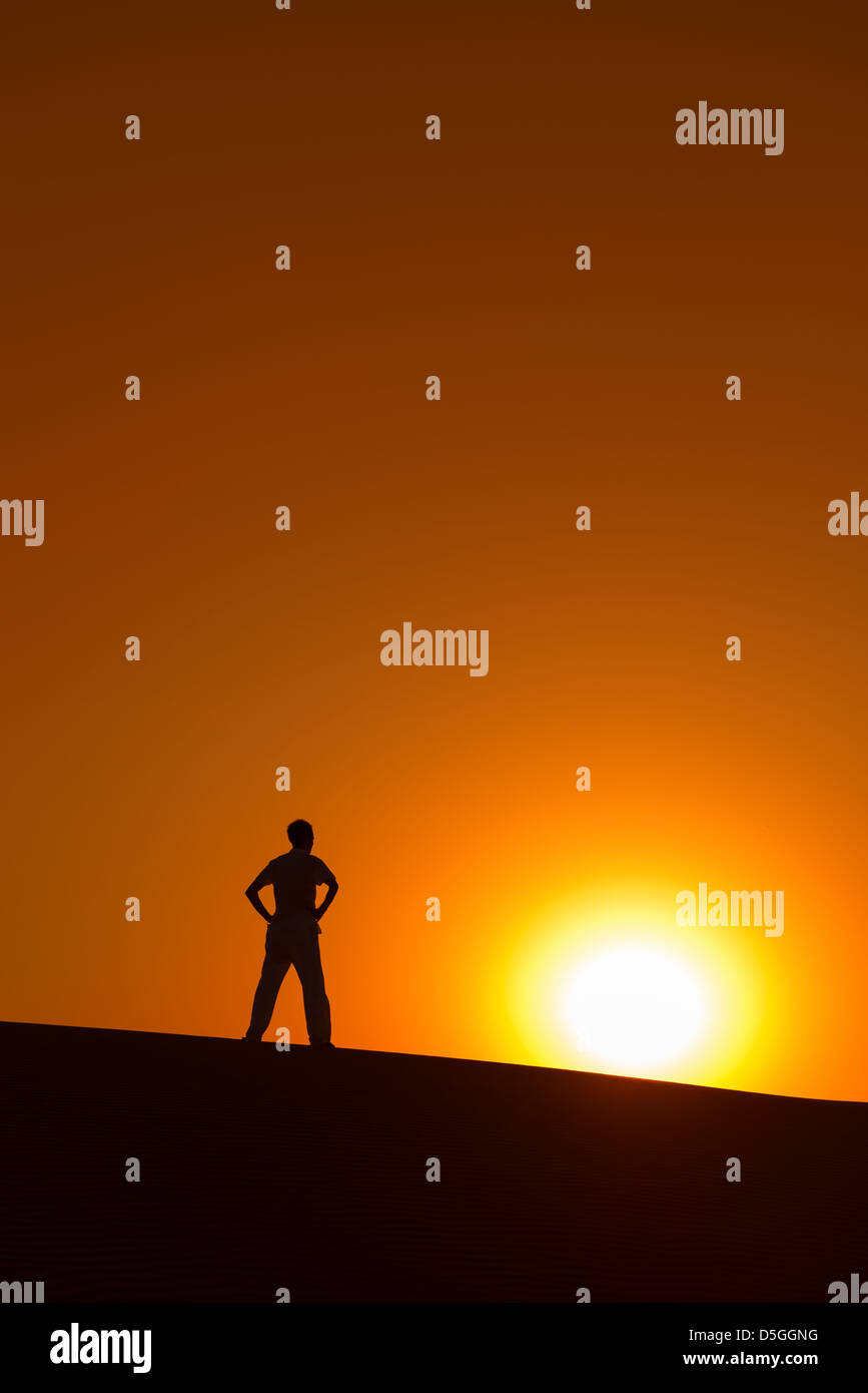 Man at orange background with big sun under horizon with heroic ...