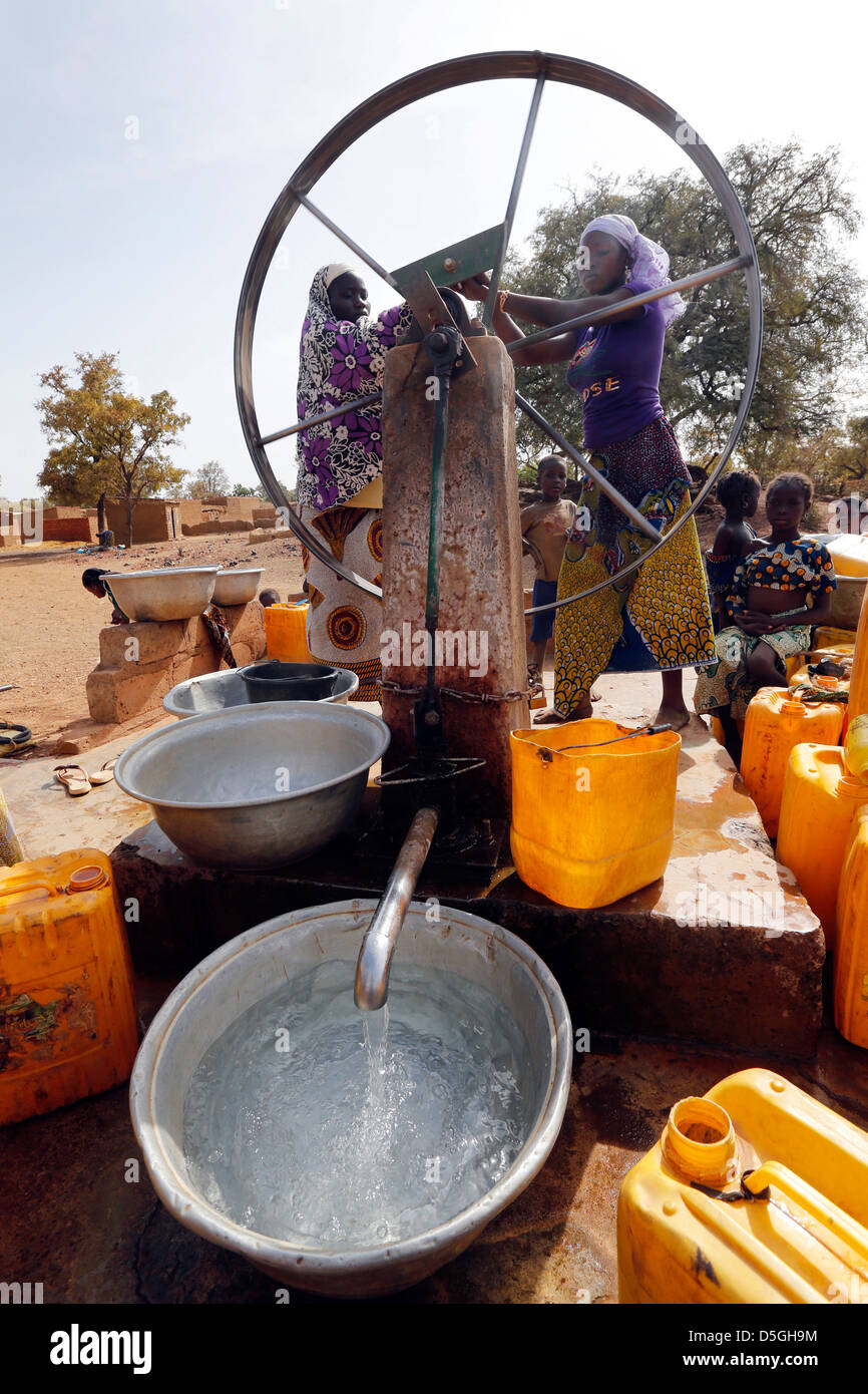 Women turn the wheel of a water pump in a village, Burkina Faso, Africa ...