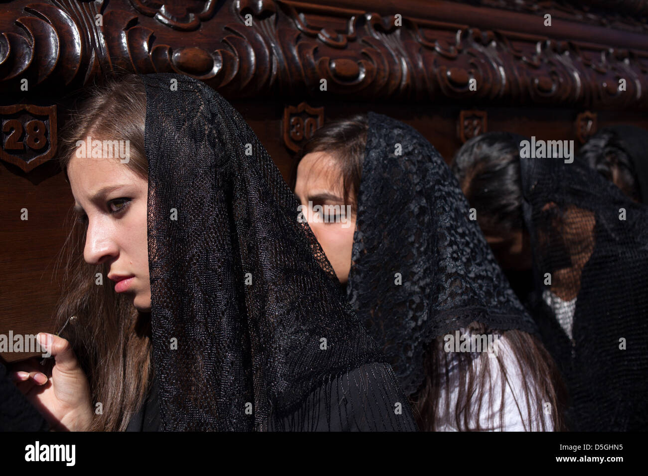 Women wearing mourning clothes carry on their shoulders an image of the ...