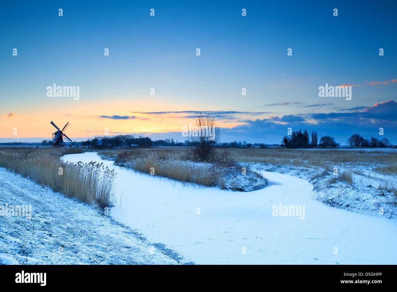 windmill by frozen river at sunrise, Groningen, Netherlands Stock Photo ...