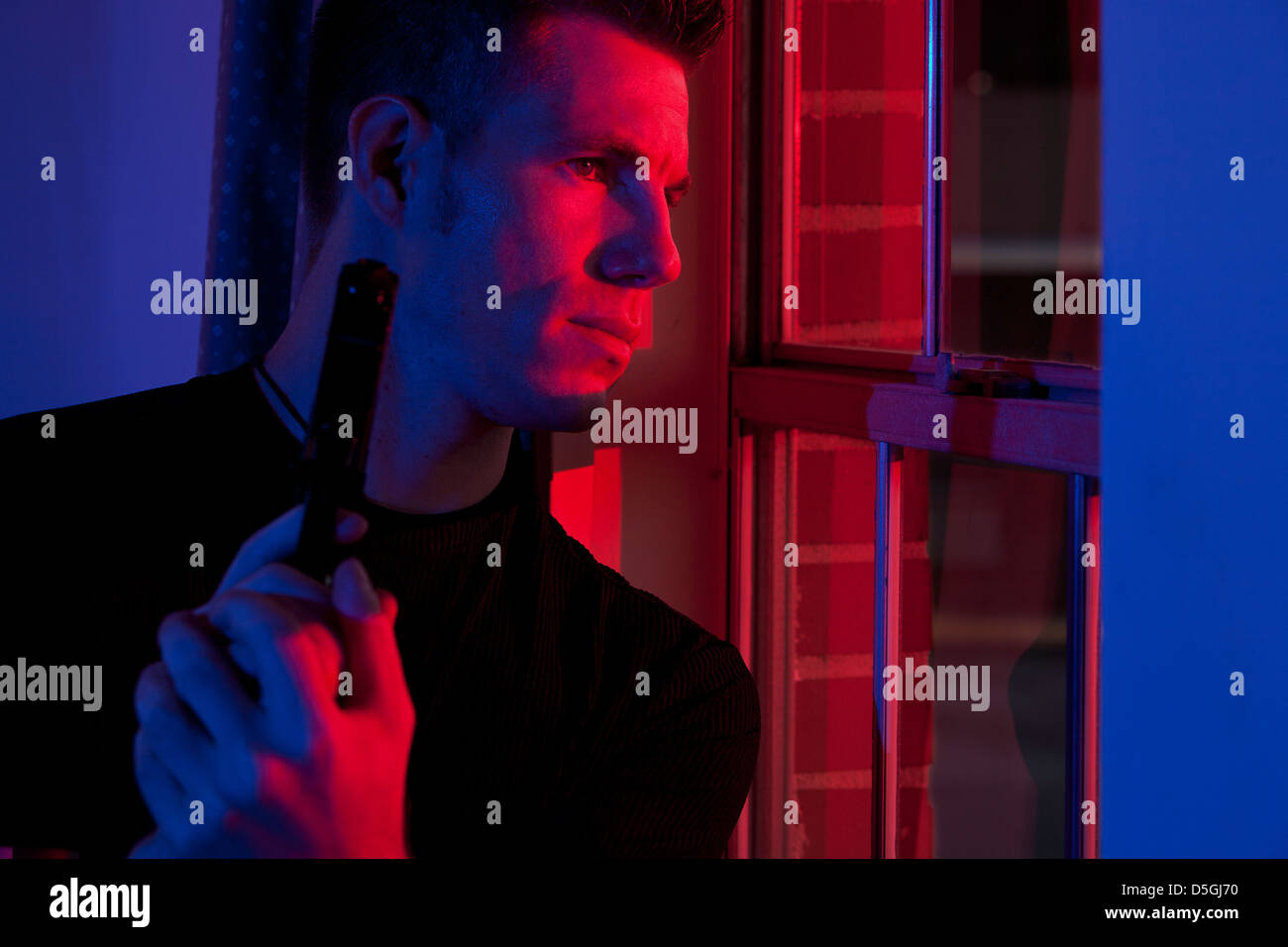Man with gun looking out window Stock Photo - Alamy