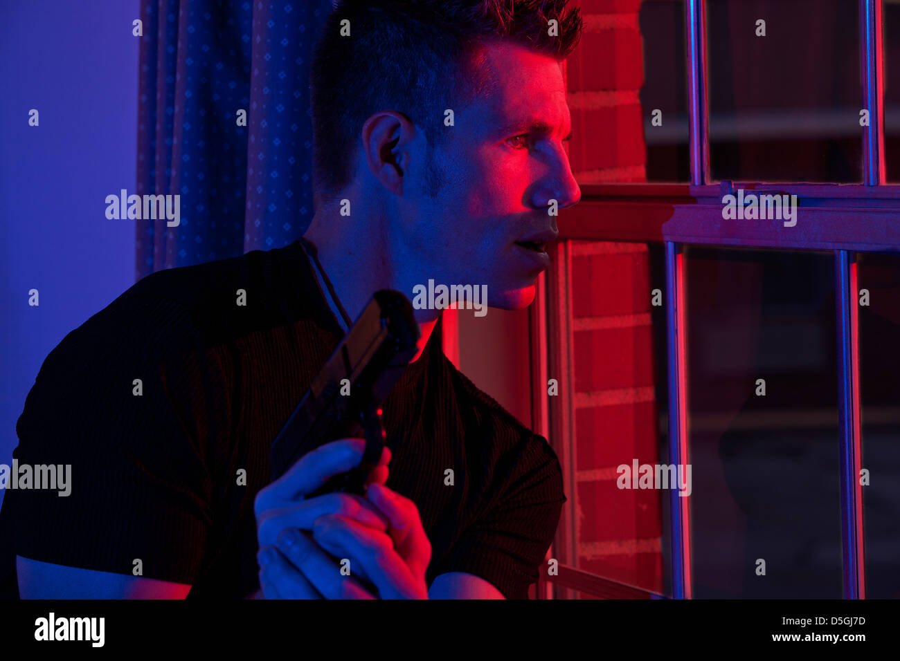 Man with gun looking out window Stock Photo - Alamy