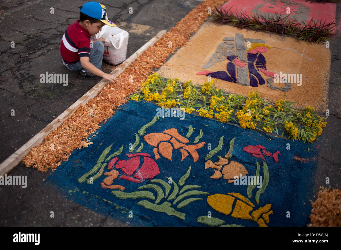 A boy helps his family to make a colored sawdust carpet during Easter ...