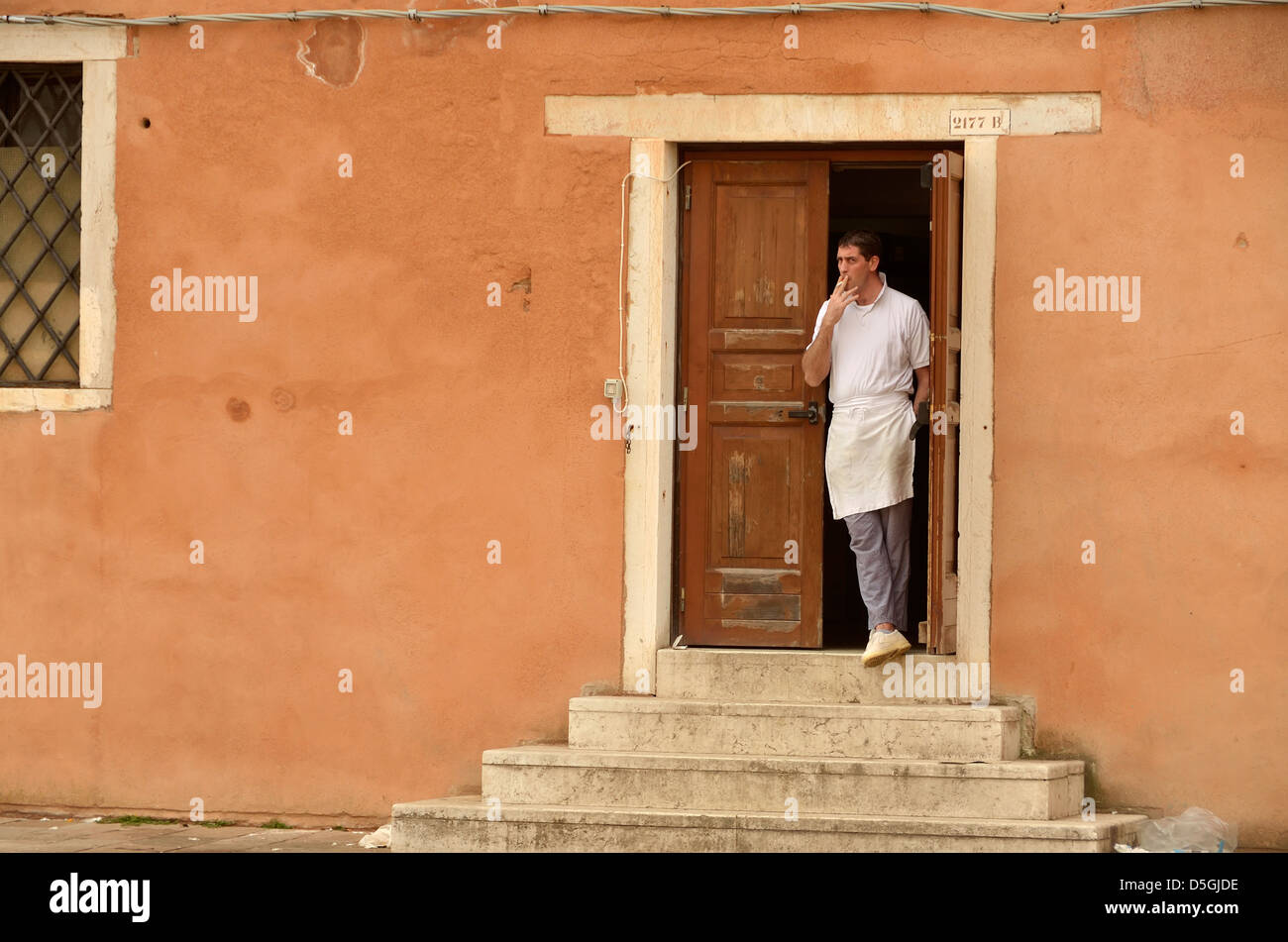 Man smoking a cigarrette in the doorway of a building in Venice, Italy ...