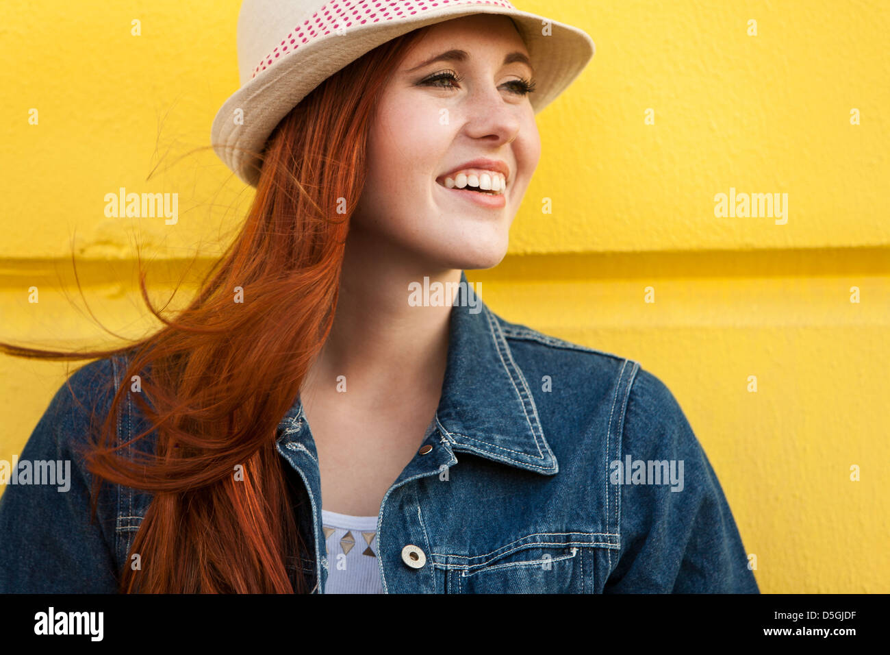 Red head woman standing by yellow wall Stock Photo - Alamy