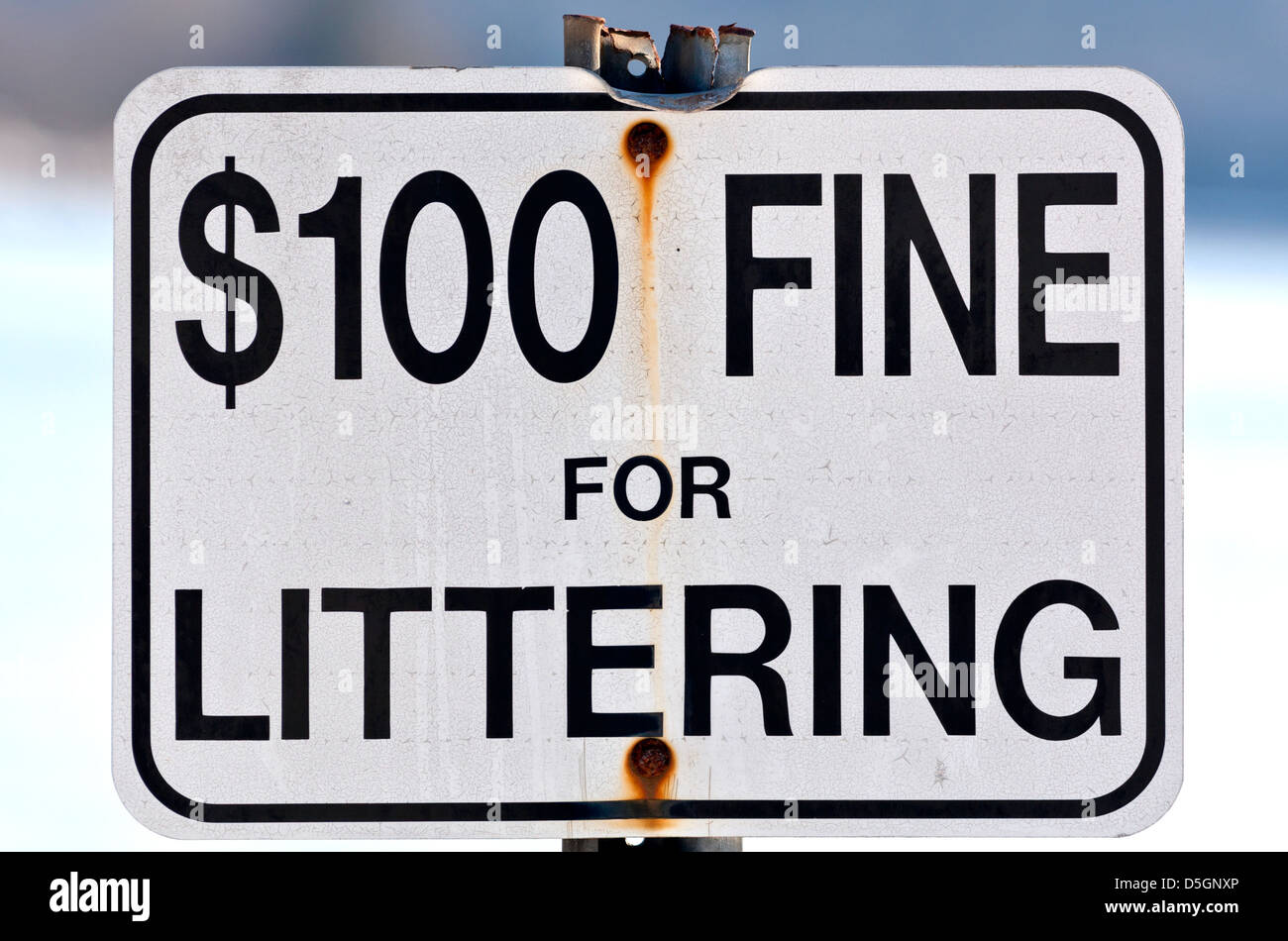 Close view of an old fine for littering sign with bent top and worn ...