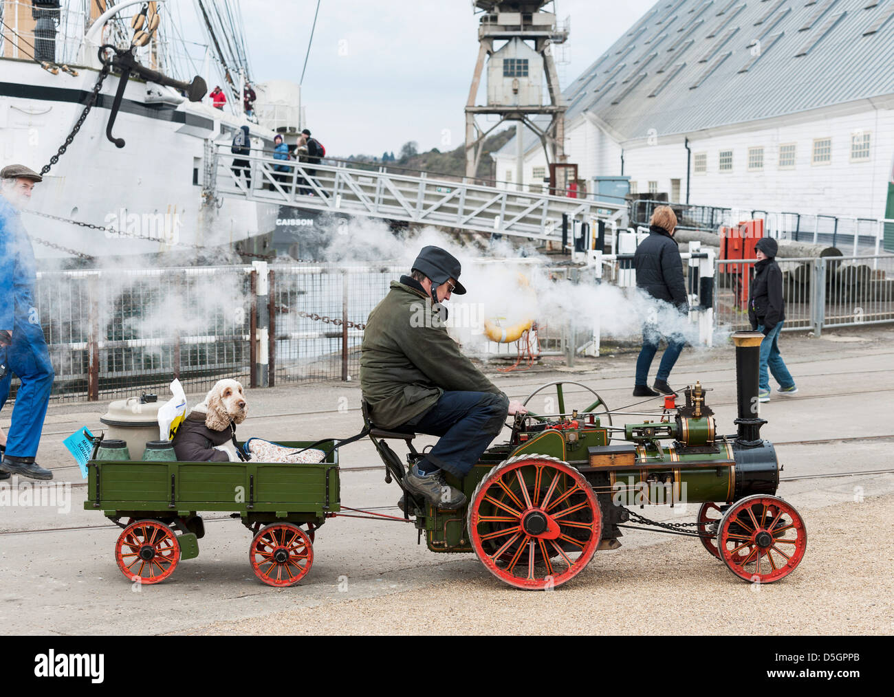 A miniature steam traction engine and trailer being driven at the ...