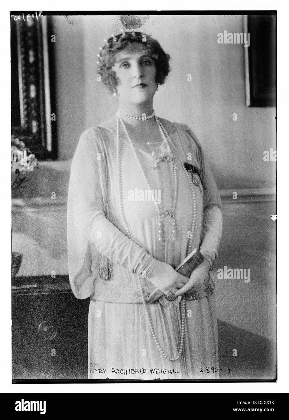 A formal portrait of Lady Archibald Weigall, shown with a fan, gloves ...