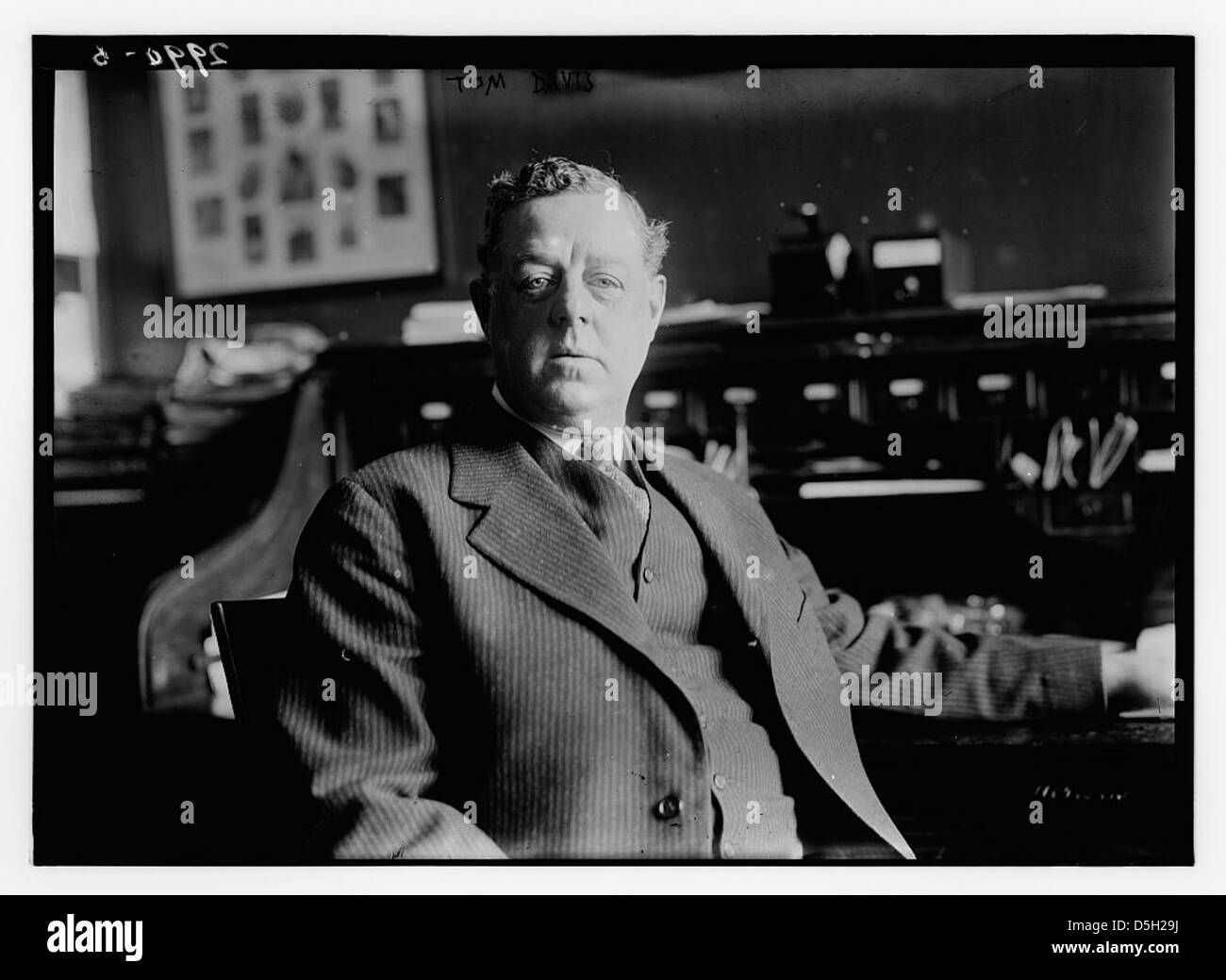 A portrait of Tom Davis seated at a desk, dressed in a pinstripe suit ...