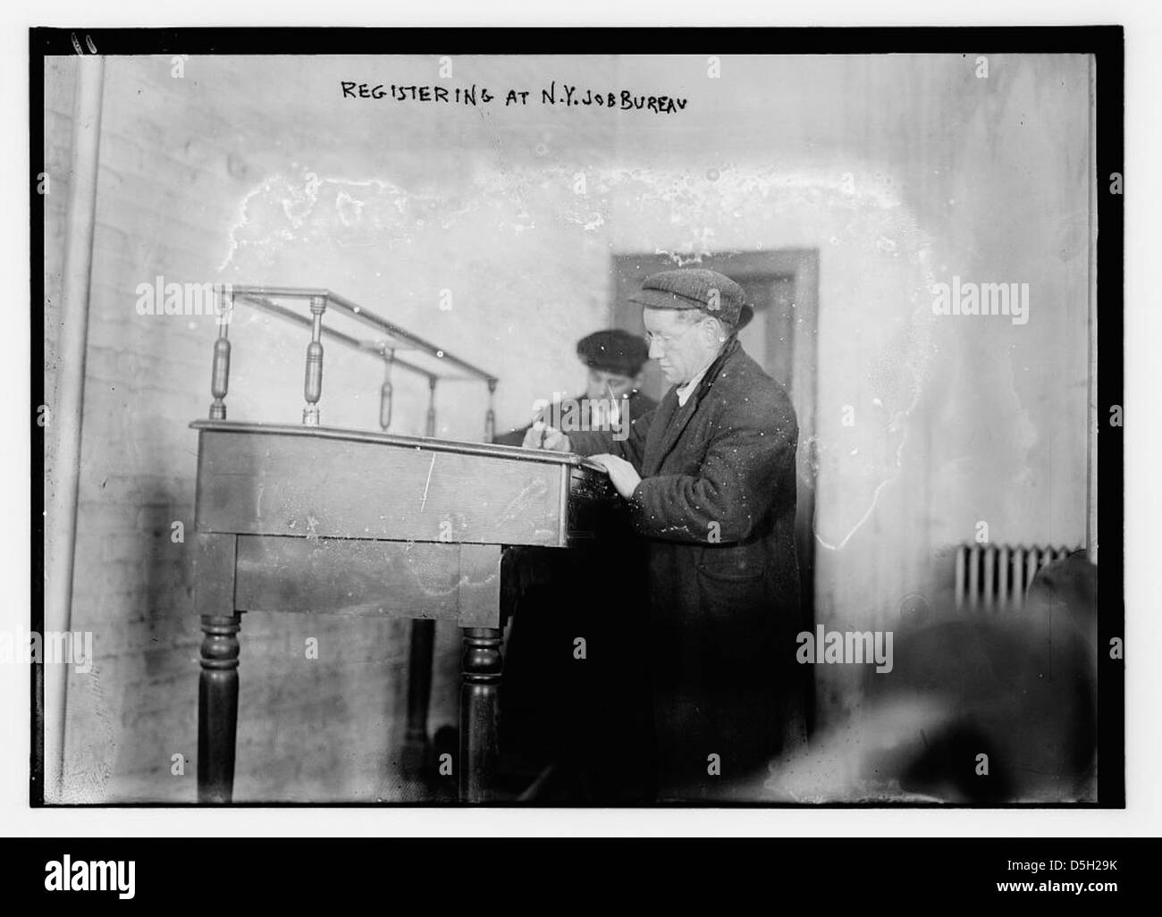 A photograph showing individuals registering at a New York job bureau ...