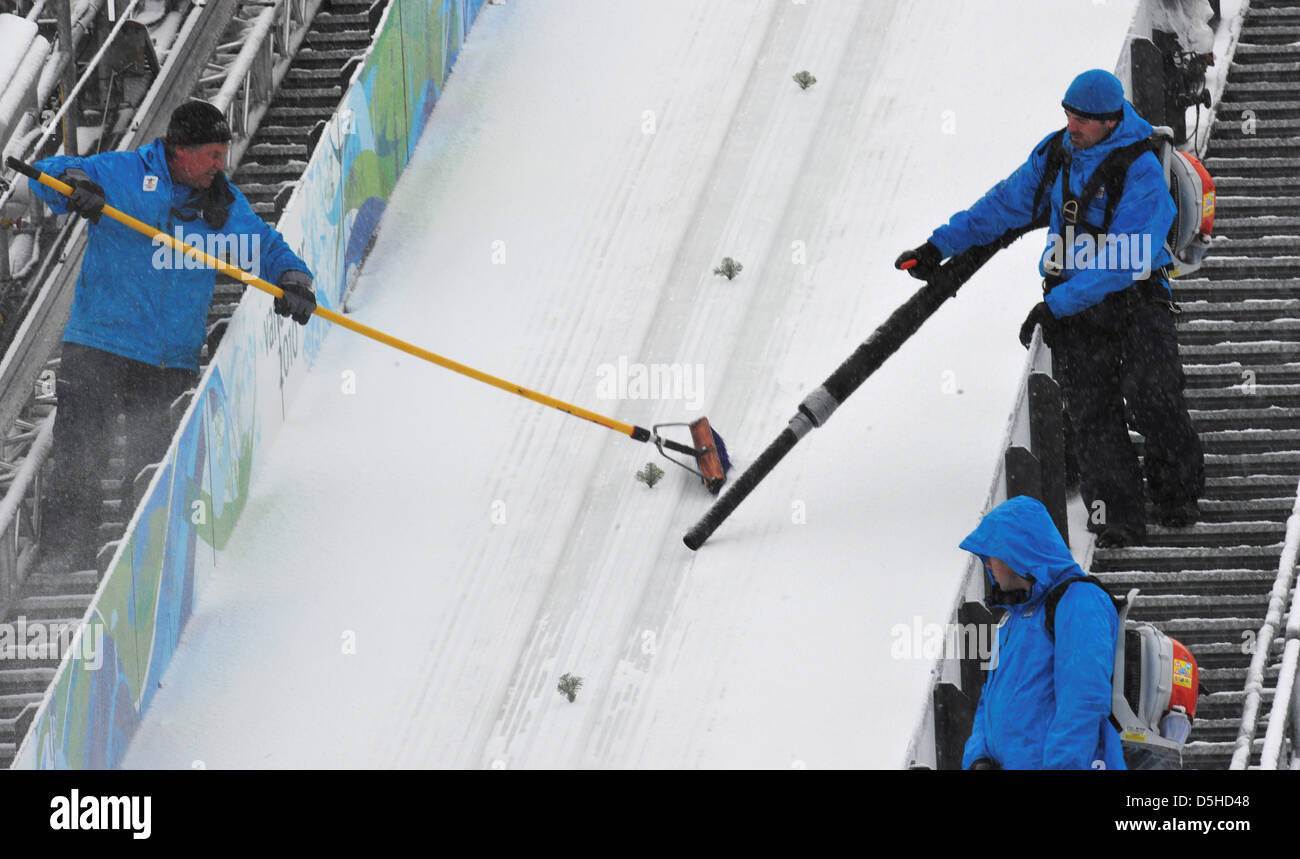 Workers shovel snow out of the inrun during the Nordic Combined ski ...