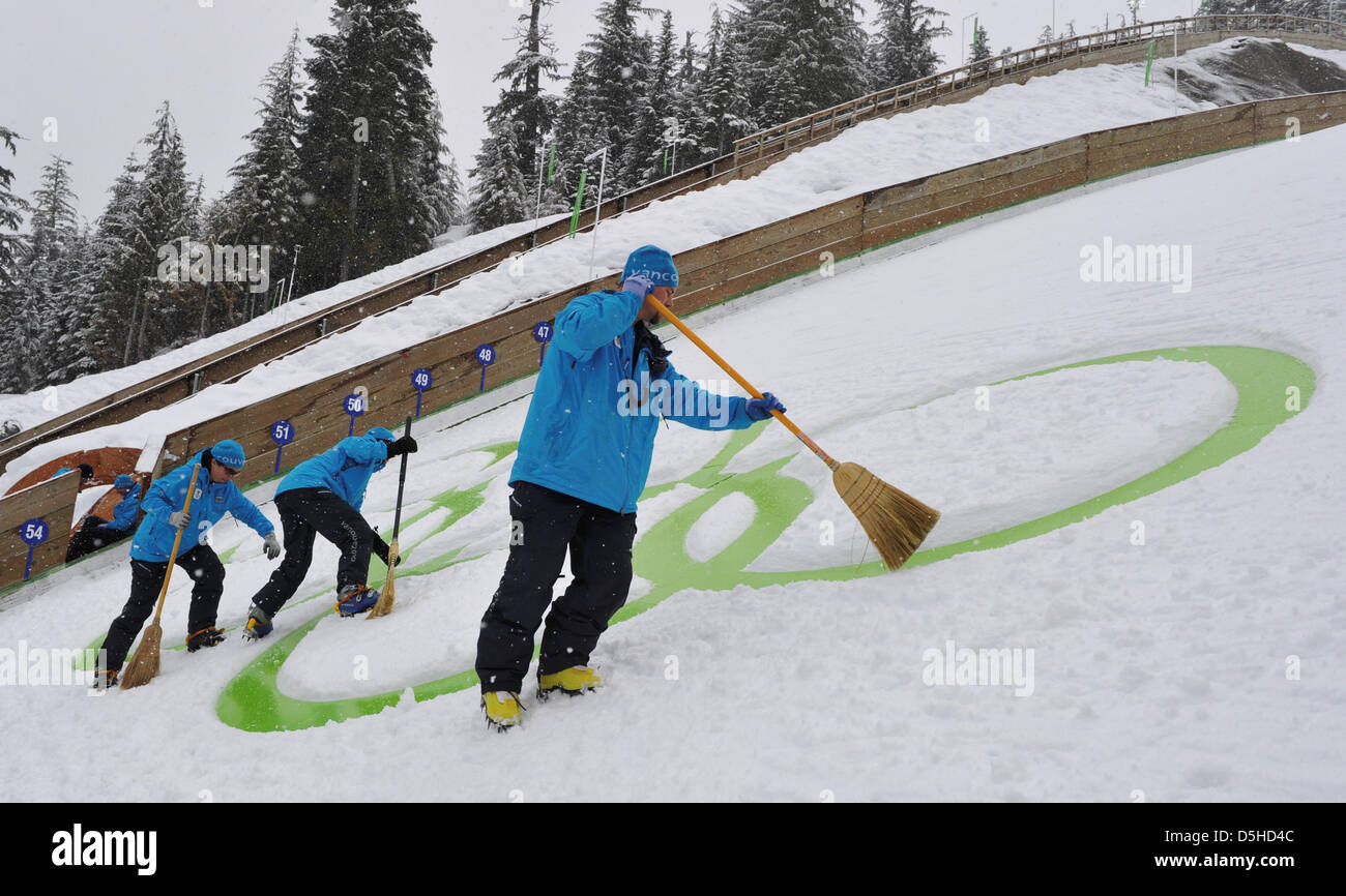 Workers shovel snow out of the inrun during the Nordic Combined ski ...