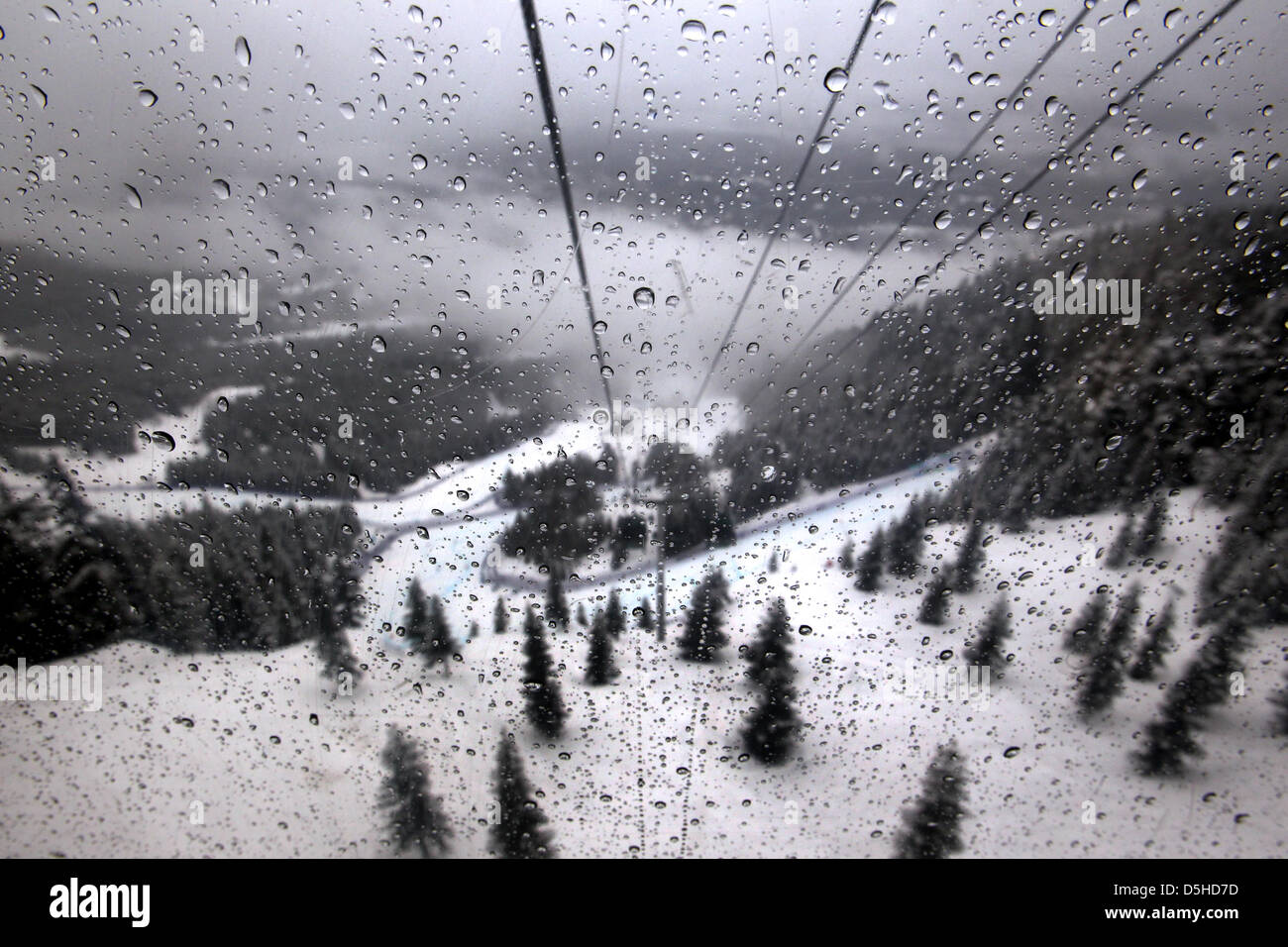 General view of the slope through the rain-covered window of the car of ...