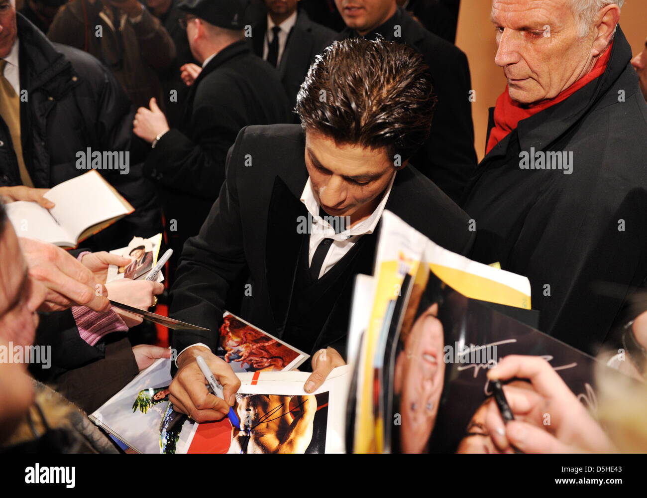 Indian actor Shah Rukh Khan signs autographes as he arrives for the ...