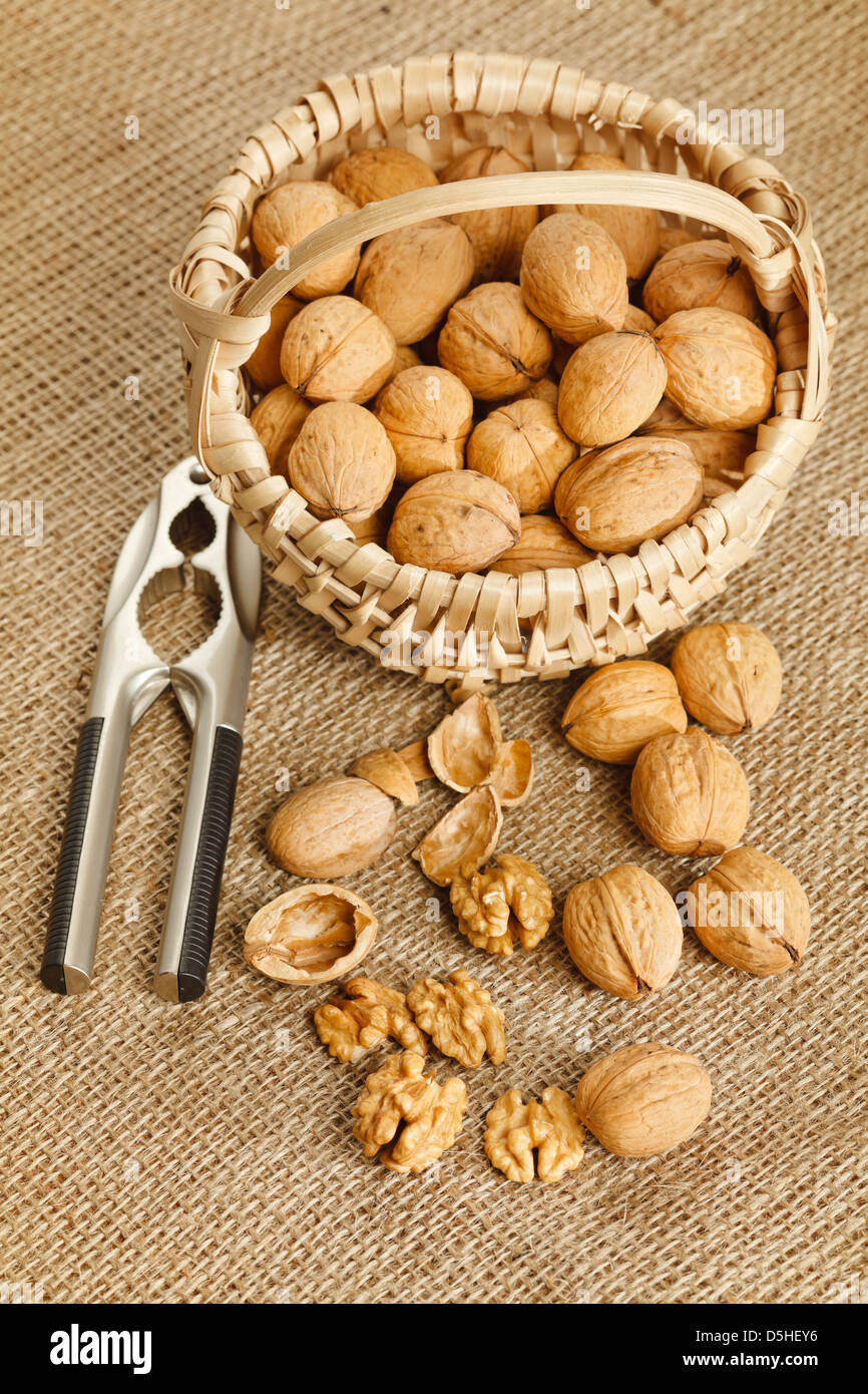 Walnuts in wicker basket and nutcracker on linen background Stock Photo ...