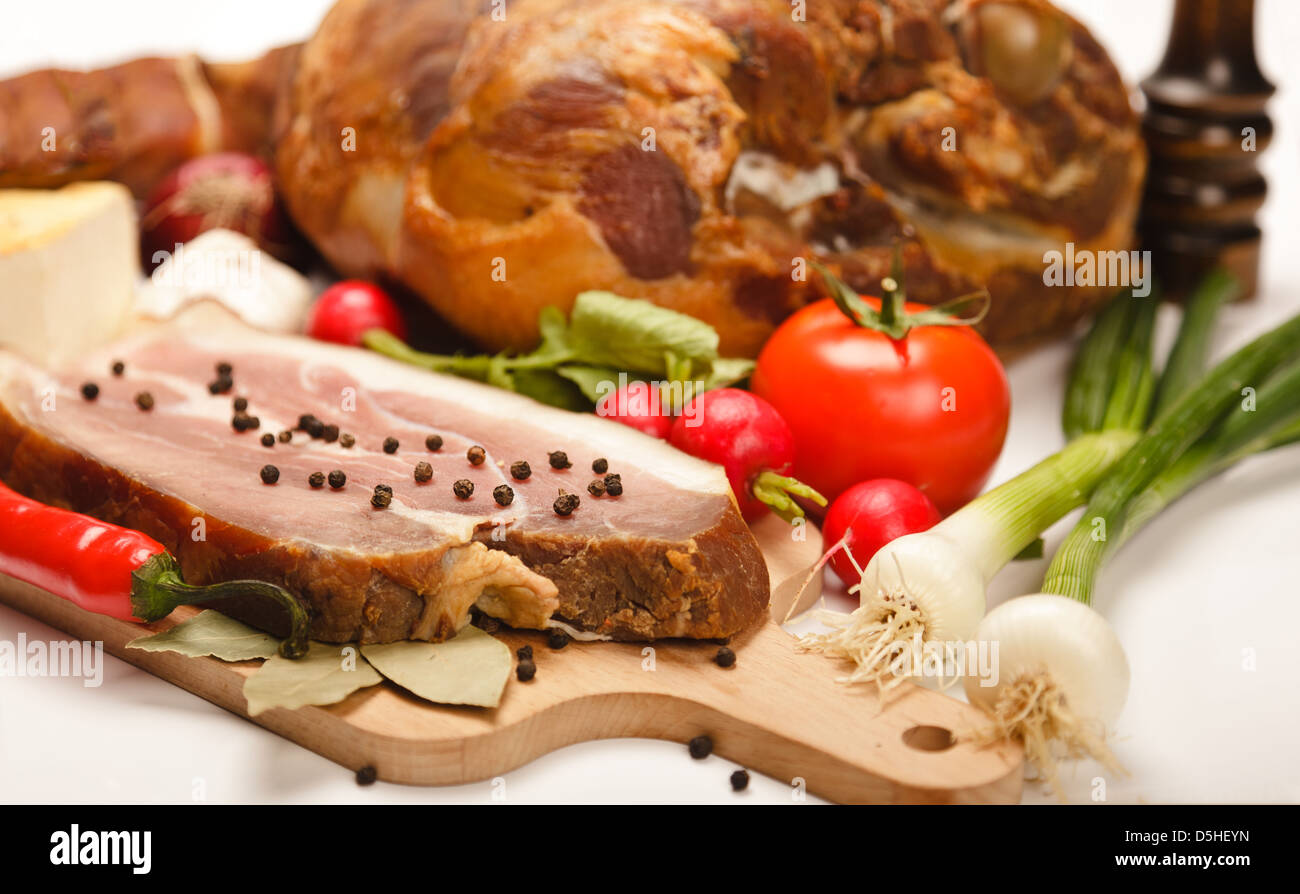 Traditional smoked pork ham slice and whole ham in background ...
