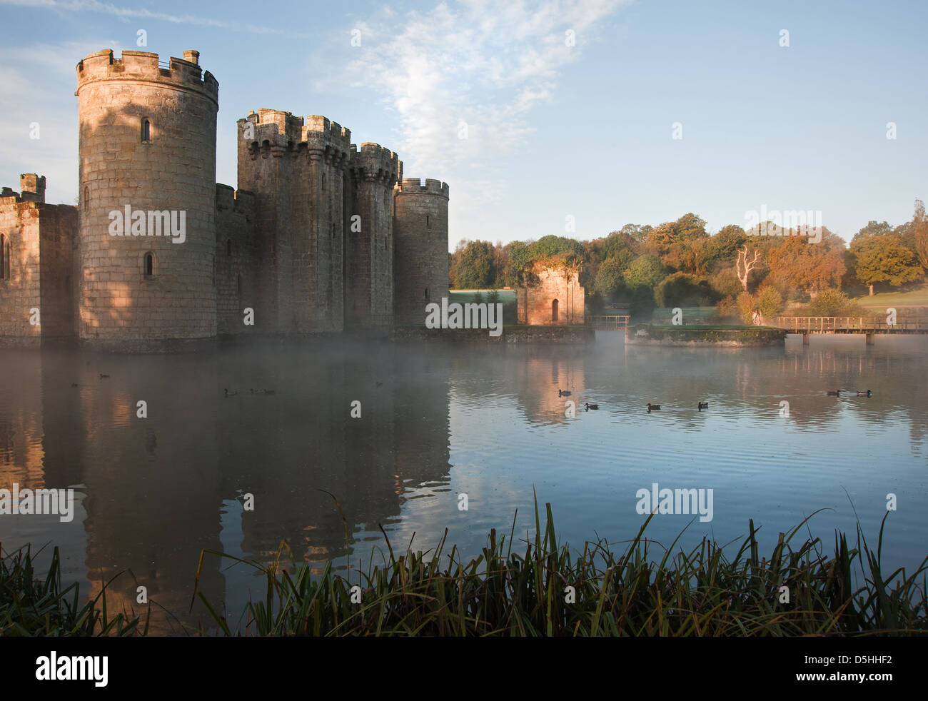 Beautiful medieval castle and moat at sunrise with mist over moat and ...