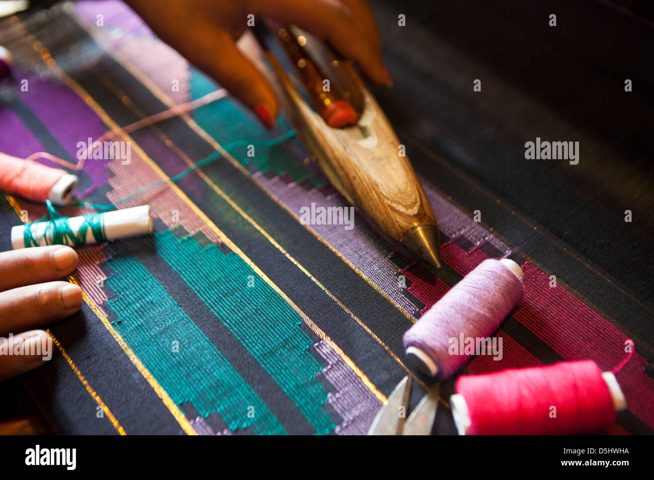 Cotton thread on traditional Nepalese material being crafted by a woman ...