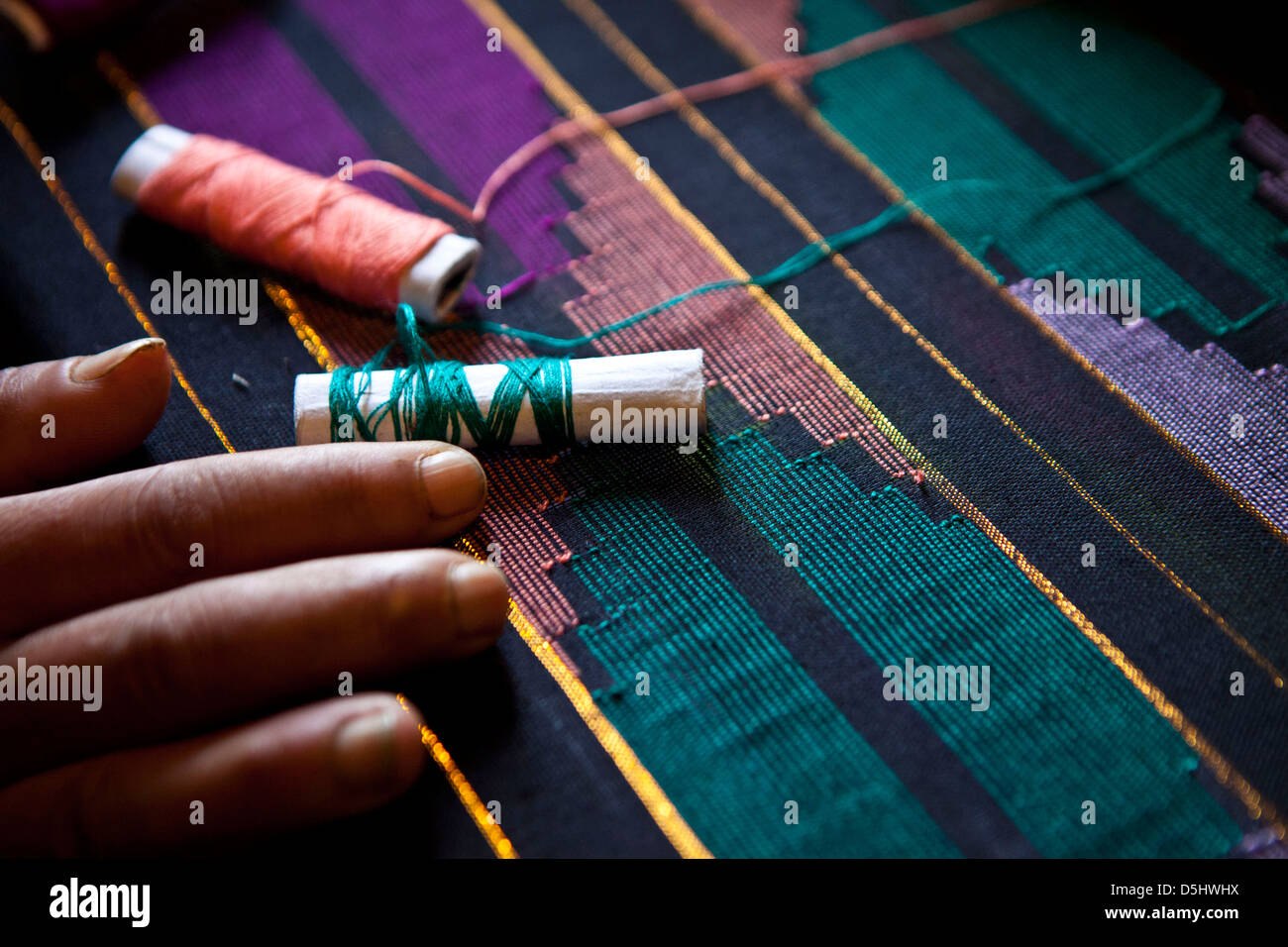 Cotton thread on traditional Nepalese material being crafted by a woman ...