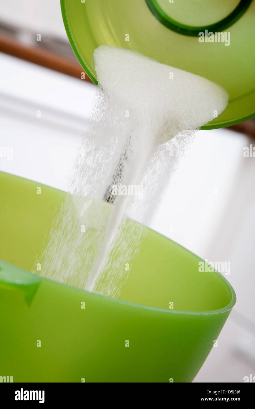Pouring white sugar in to green bowl Stock Photo - Alamy