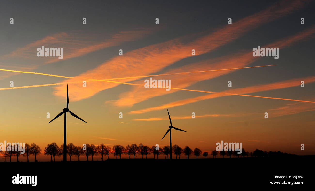Wind turbines silhouette against the rising sun on a field near ...